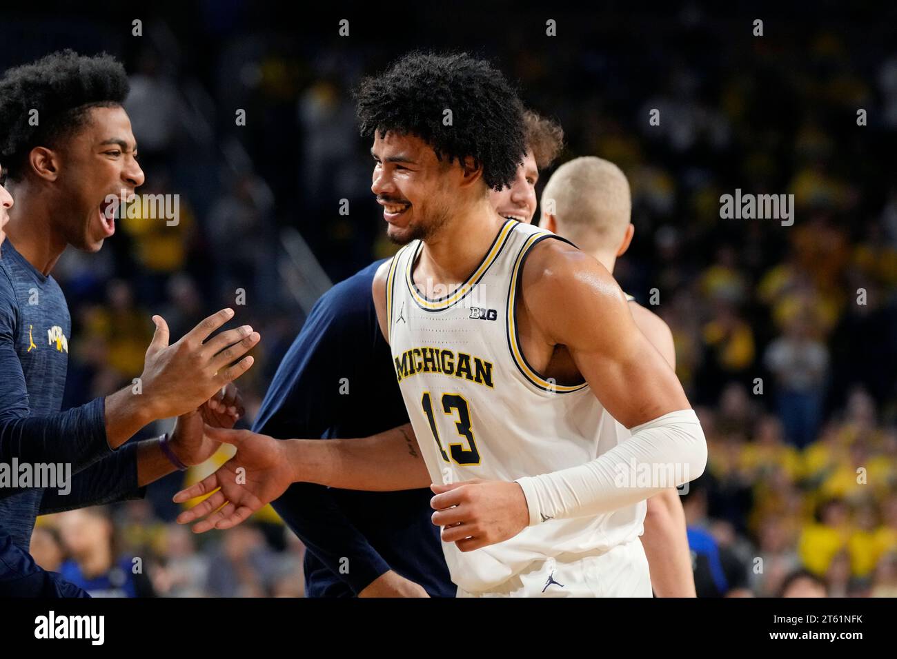 Michigan forward Olivier Nkamhoua (13) is greeted by guard Jace Howard ...