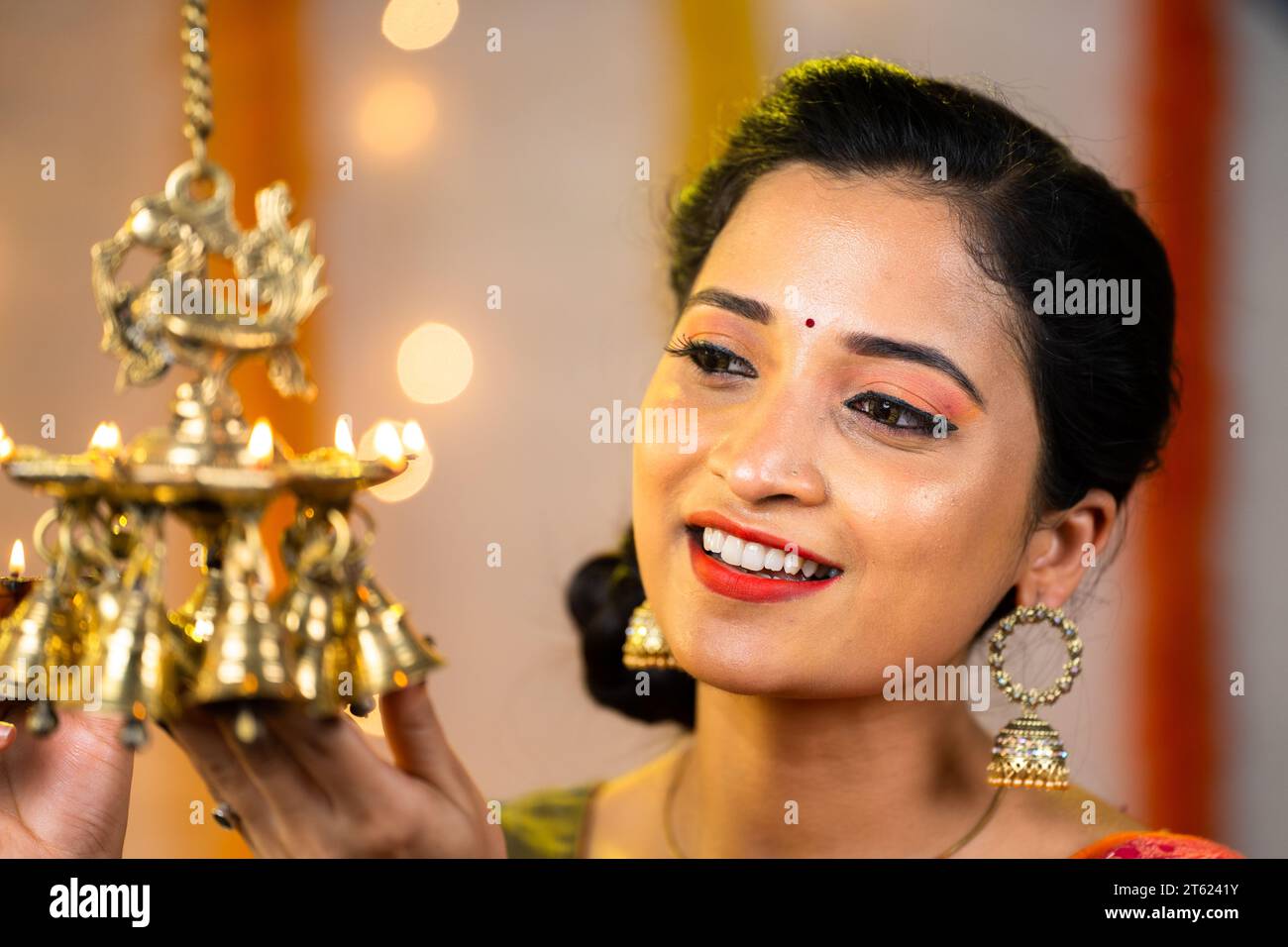 Close Up Head Shot Of Happy Young Indian Girl Lighting Up Hanging Oil
