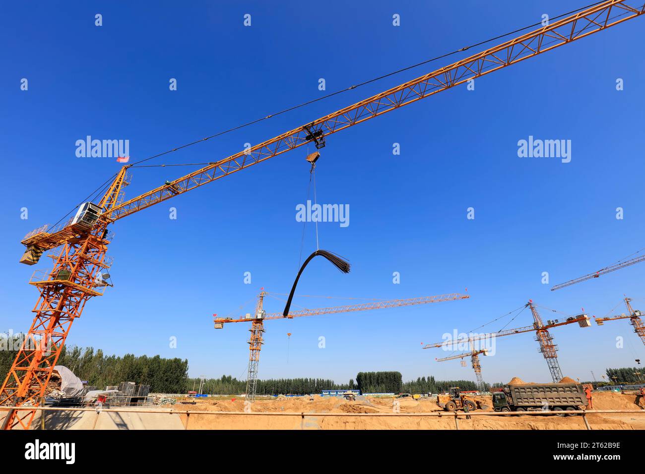 Tower crane hoisting materials in the construction site Stock Photo - Alamy