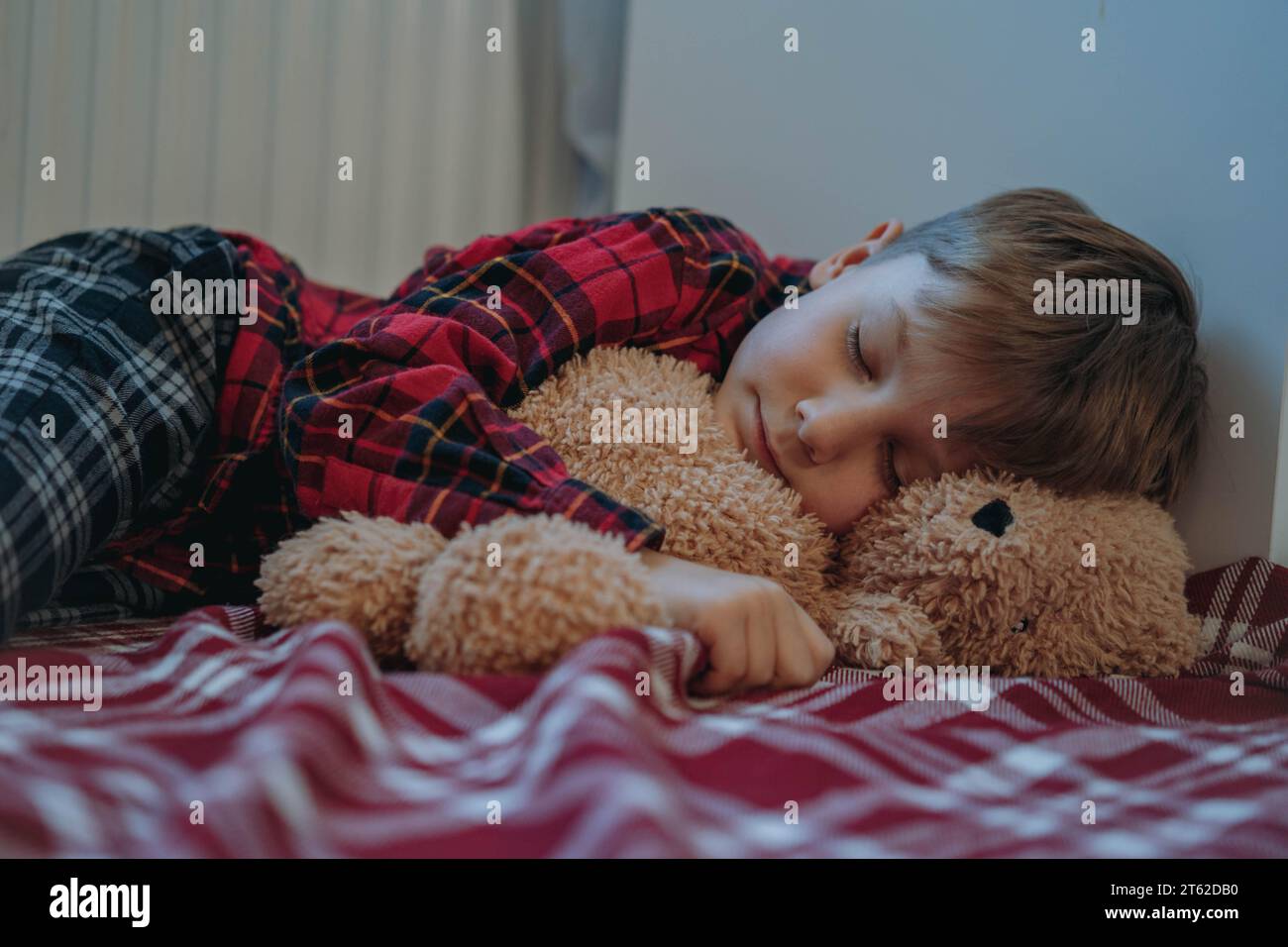 cute little boy falling asleep by heater hugging teddy bear waiting for ...