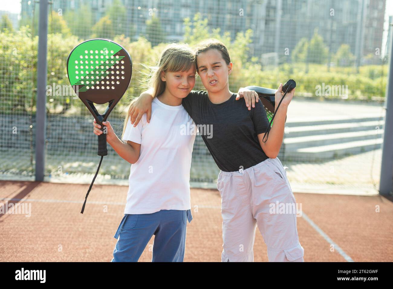 Teenage girls with racquets and balls standing in padel court, looking ...