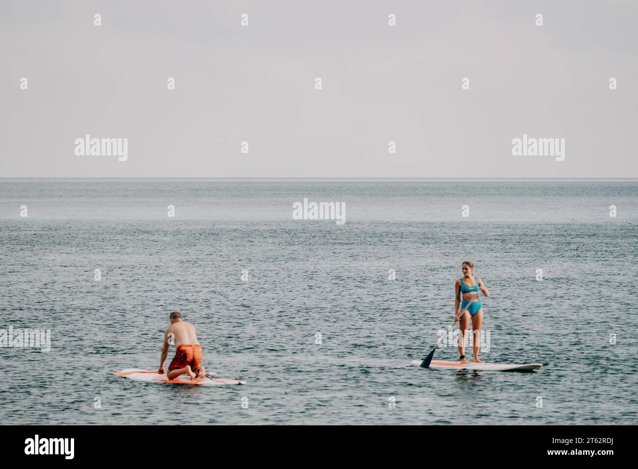 Active mature male paddler with his paddleboard and paddle on a sea at summer. Happy senior man ...