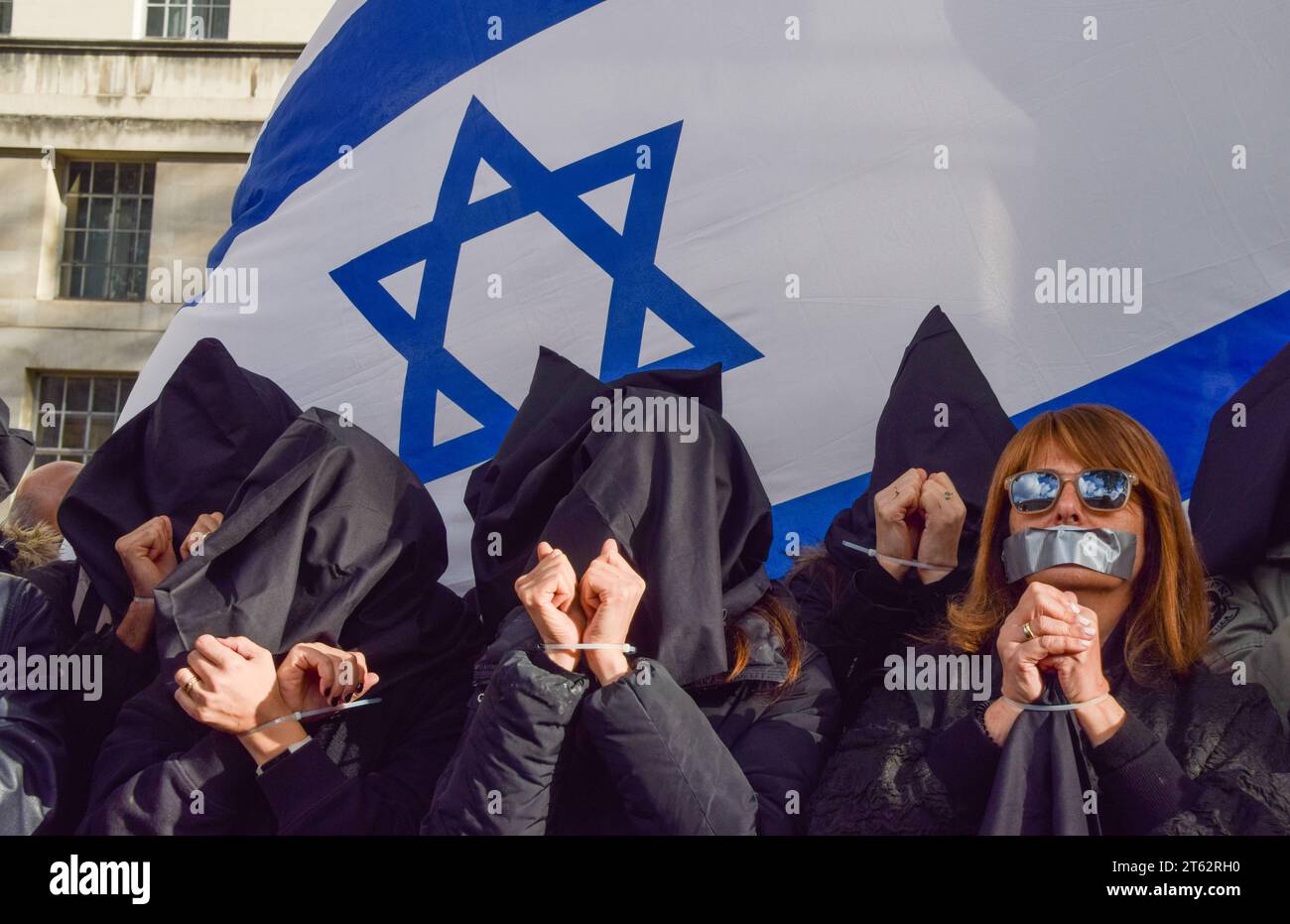 London, UK. 7th November 2023. Protesters have their hands tied, mouths ...