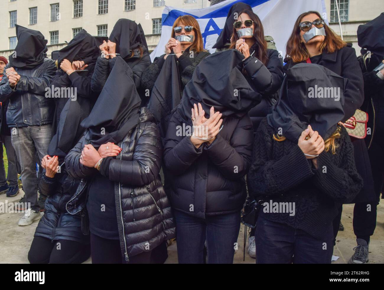 London, UK. 7th November 2023. Protesters have their hands tied, mouths ...