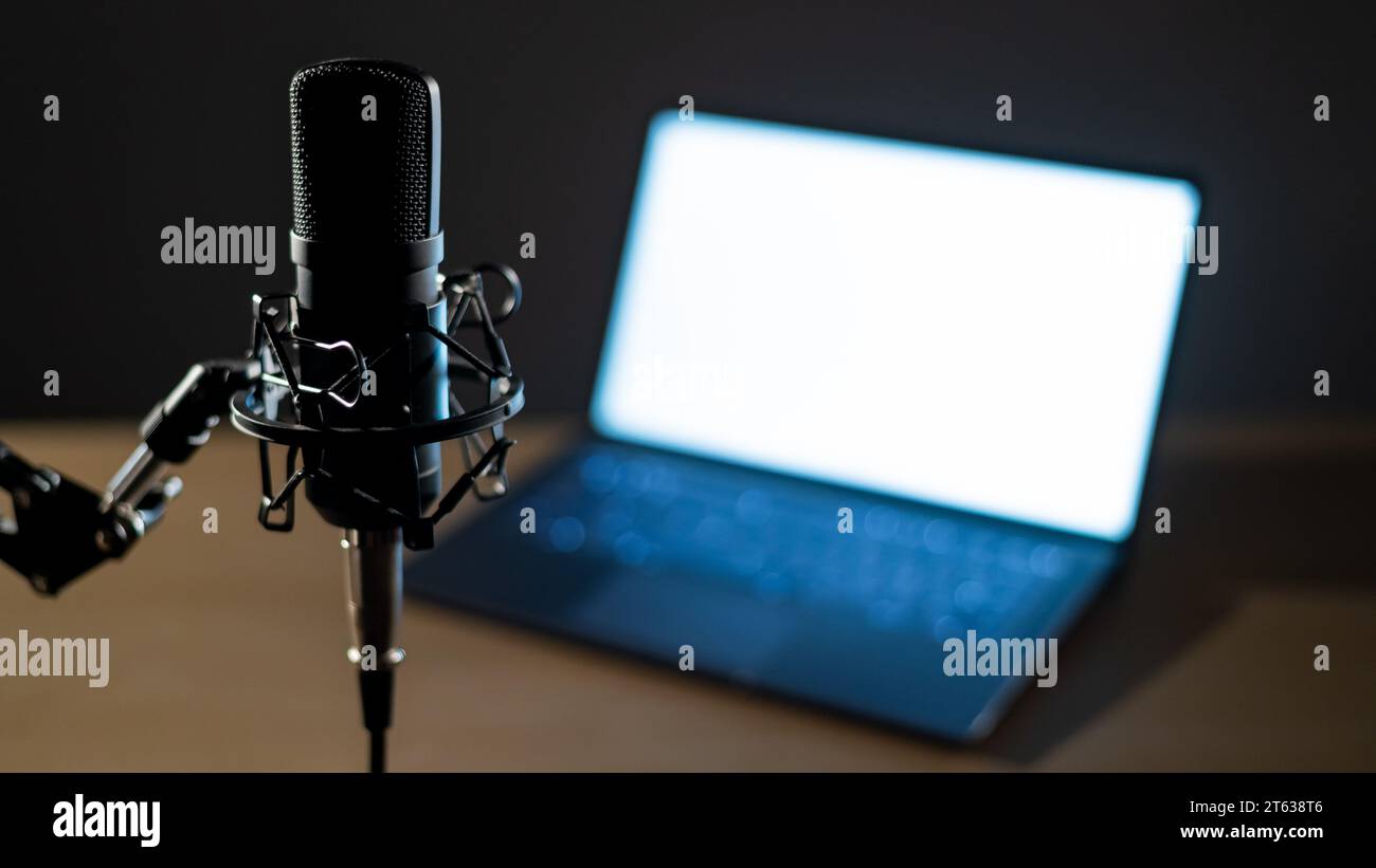 Professional microphone and laptop with white screen in the dark ...