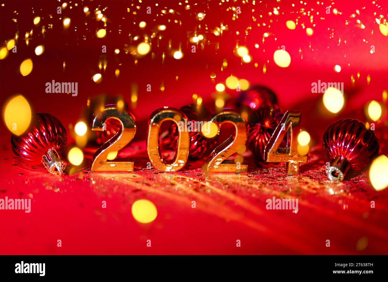 2024 gold colored numbers and glittering confetti on a vivid bright red ...