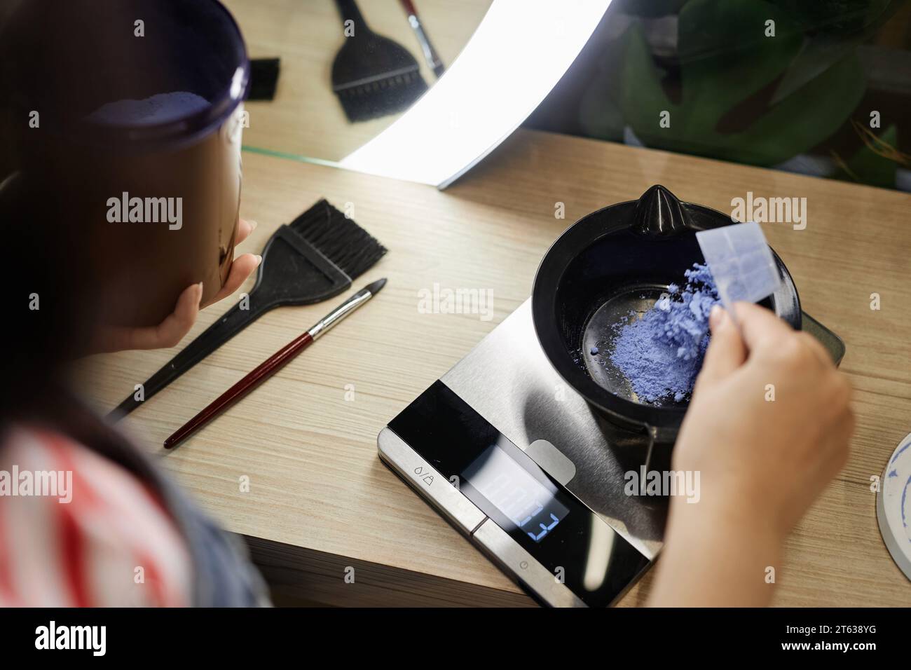 High angle closeup of hairstylist mixing bleach in plastic bowl and ...