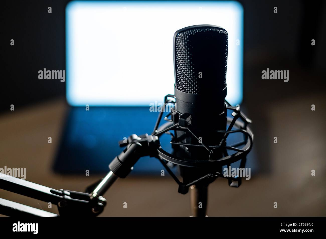 Professional microphone and laptop with white screen in the dark ...