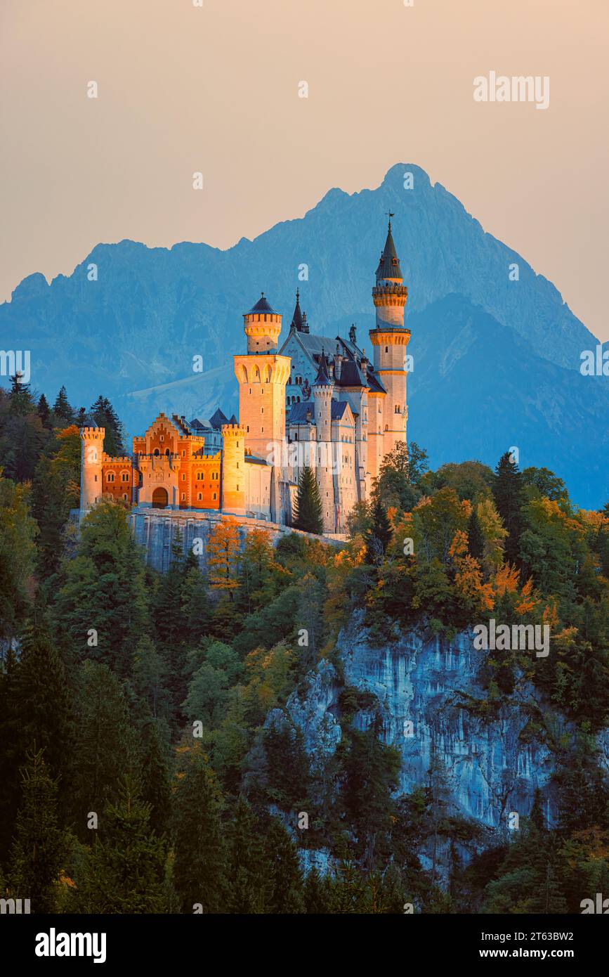 Neuschwanstein Castle illuminated after sunset surrounded by autumn ...