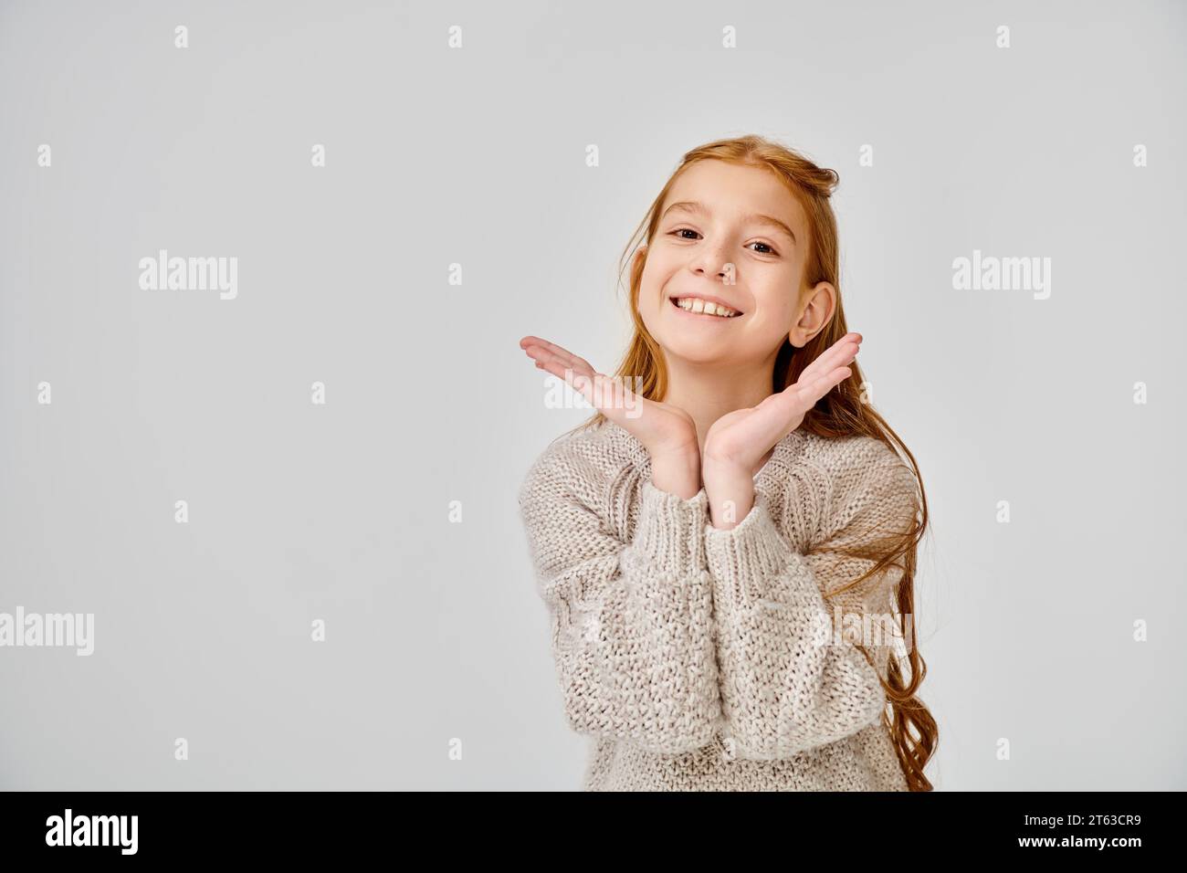pretty little girl with red hair in casual knitted sweater looking at ...