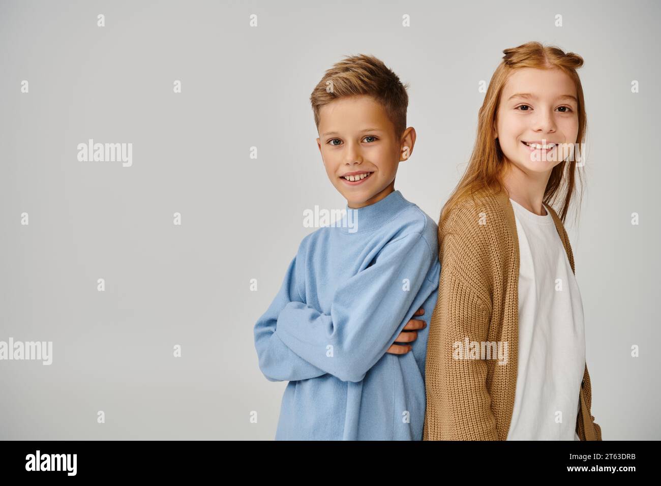 cheerful preteen children in casual warm attires posing back to back ...