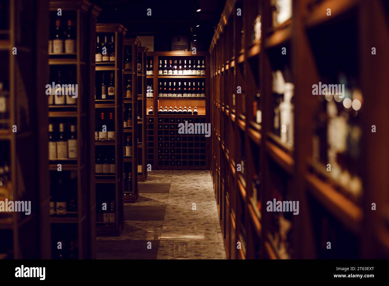 Big cellar in wine shop with wooden shelves for alcohol drinks. Long ...