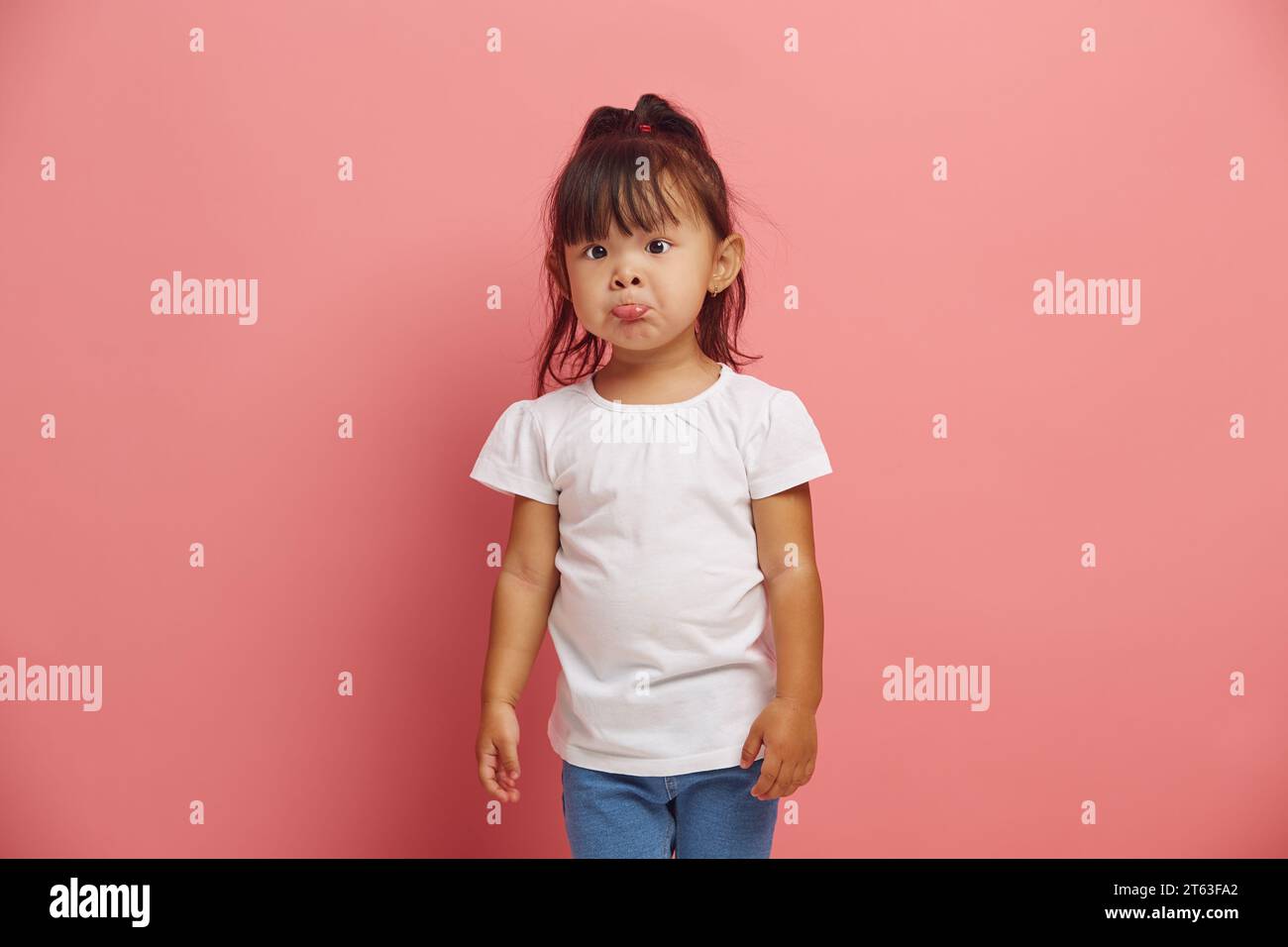 Frustrated little baby girl purses lower lip looks surprised at camera ...