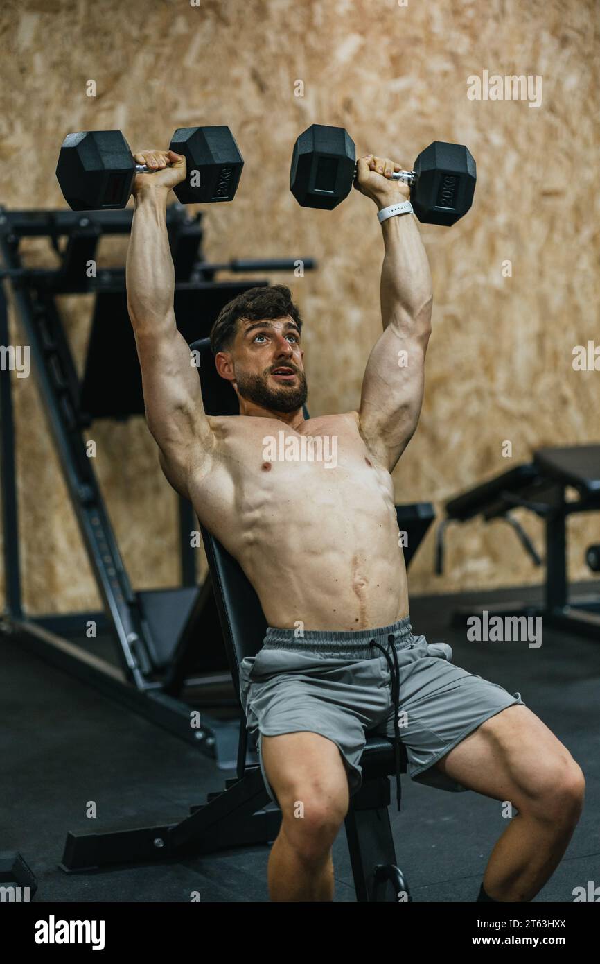 Determined man with a muscular build, pushing upwards with heavy ...