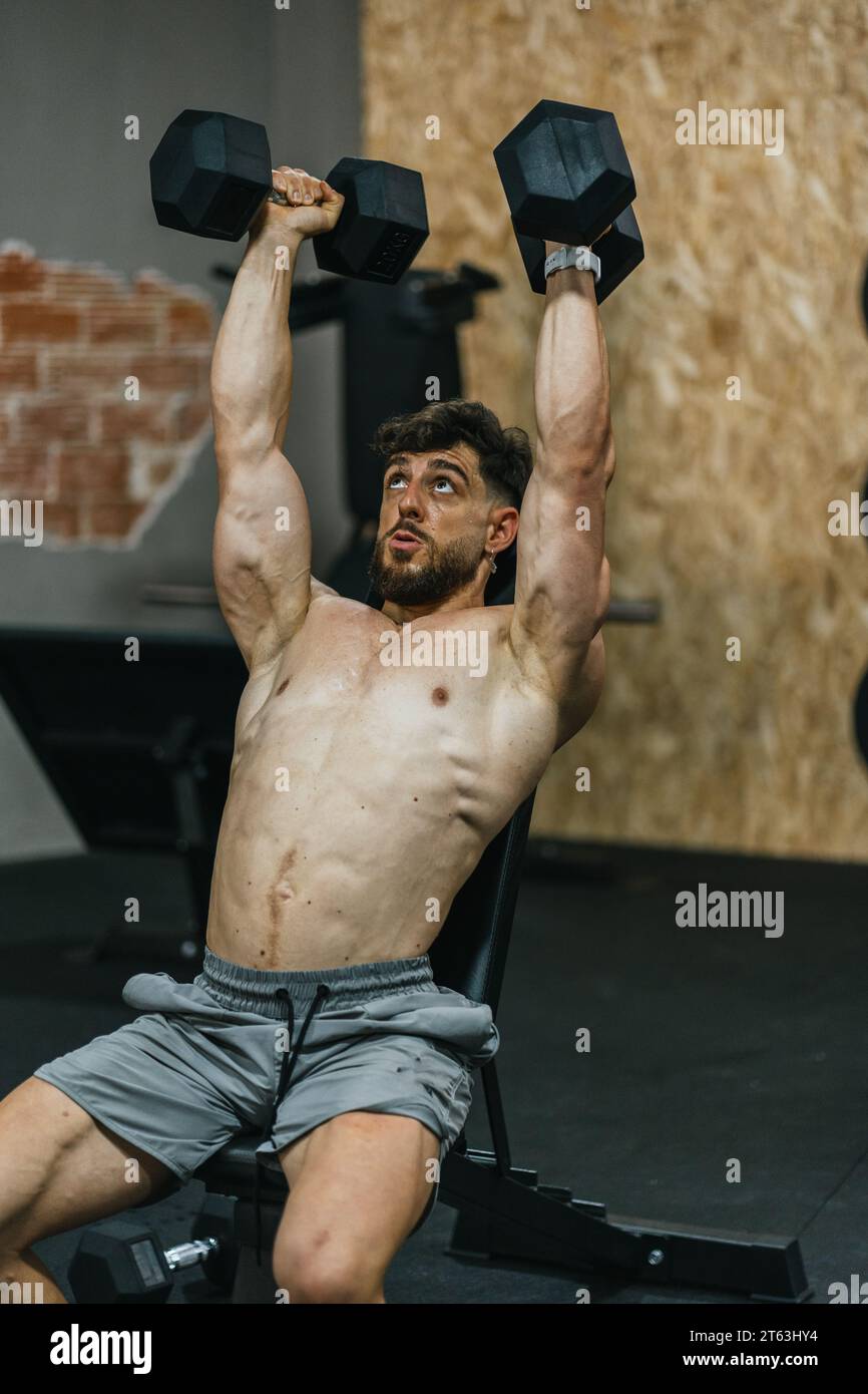 Determined man with a muscular build, pushing upwards with heavy ...