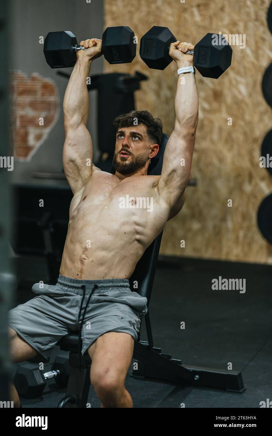 Determined man with a muscular build, pushing upwards with heavy ...