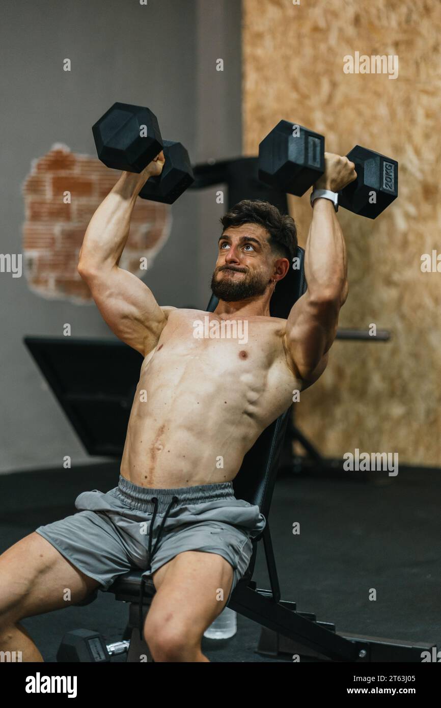 Determined man with a muscular build, pushing upwards with heavy ...