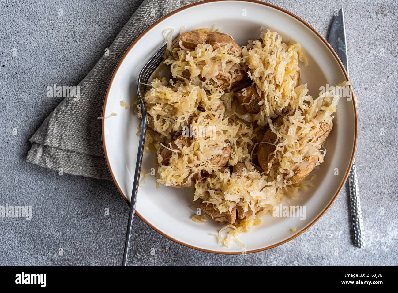 Top view of plate of jacket potato topped with fermented cabbage salad ...