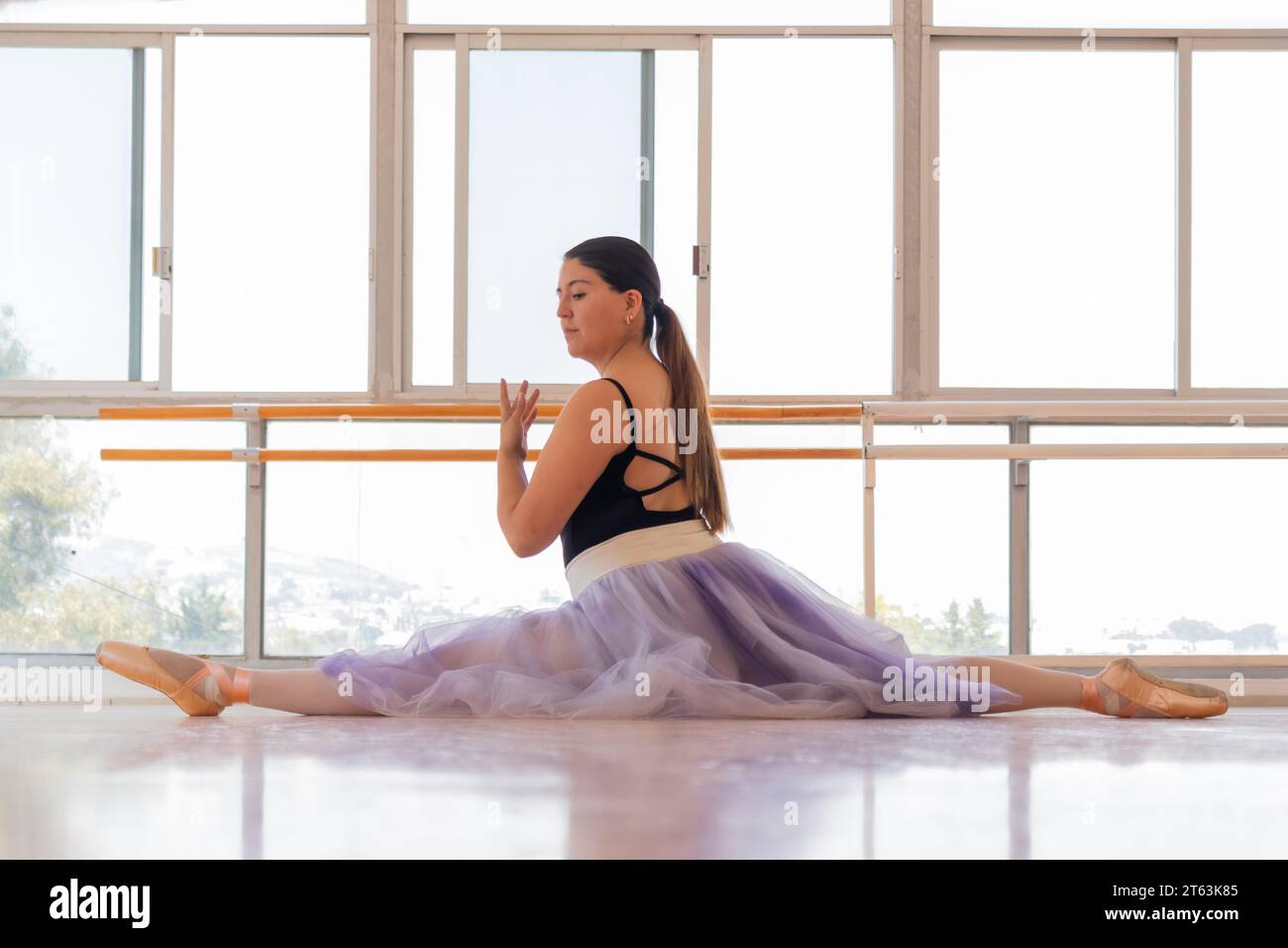 Focused ballet dancer in a black leotard with a unique back design sits ...