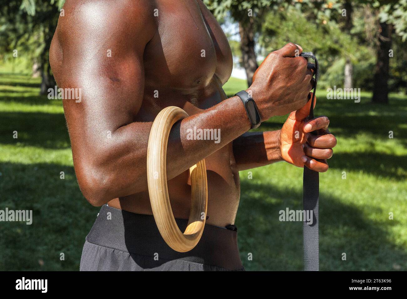 Anonymous fit black man in an outdoor setting adjusting a wooden ...