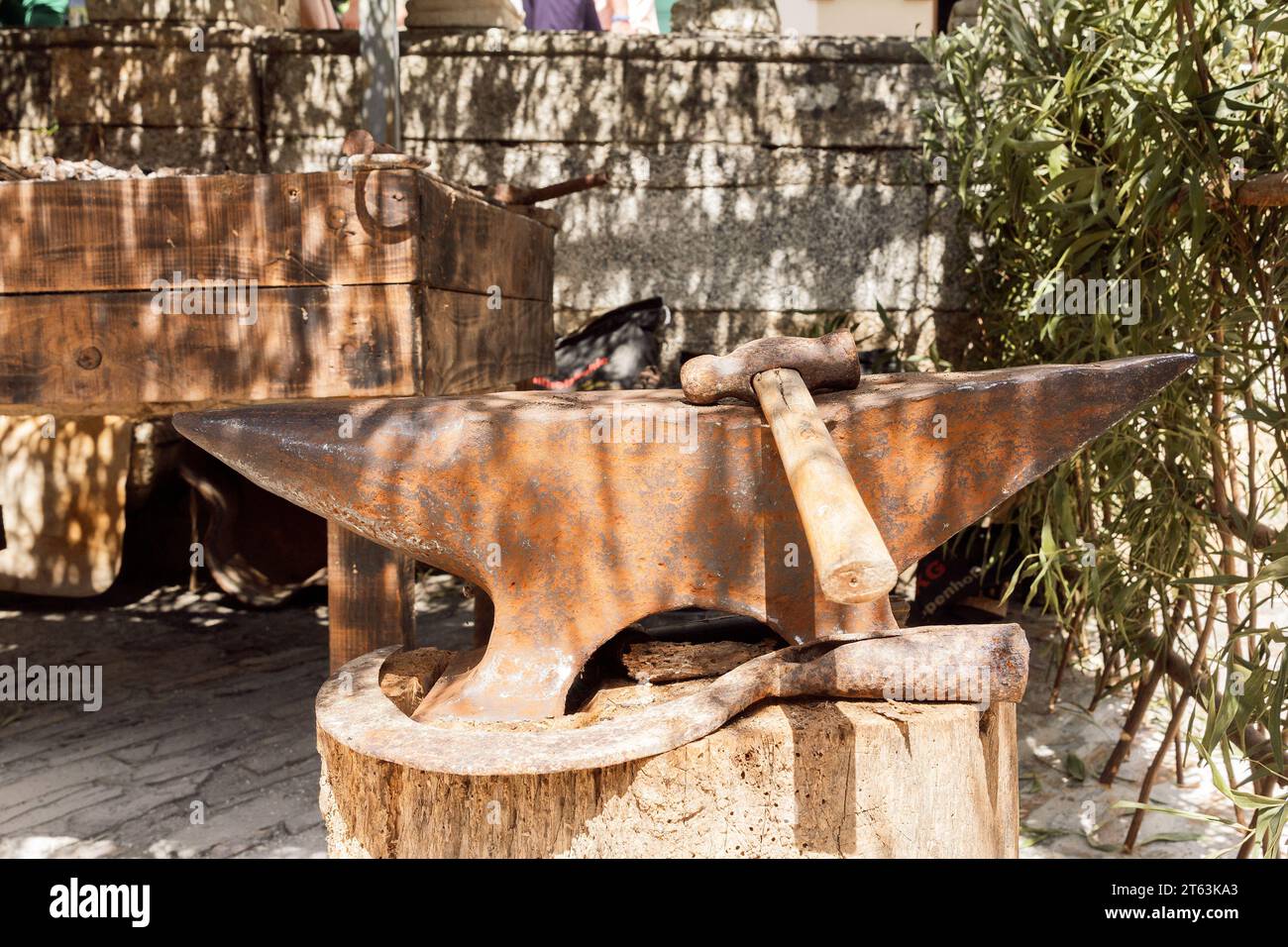 Medieval blacksmiths anvil with hammer set against a backdrop of wooden ...