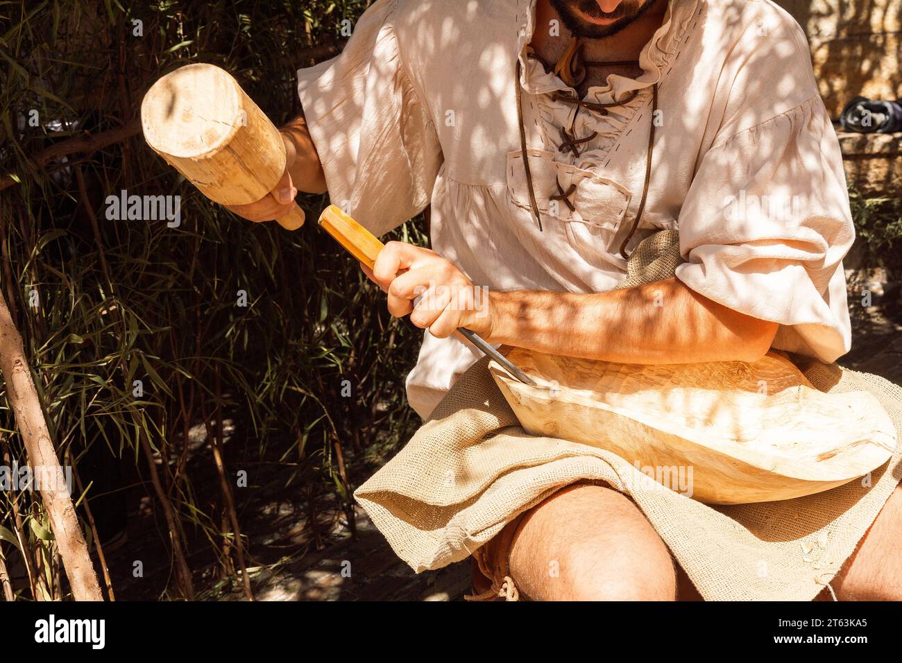Anonymous medieval craftsman in traditional attire skillfully carves a ...