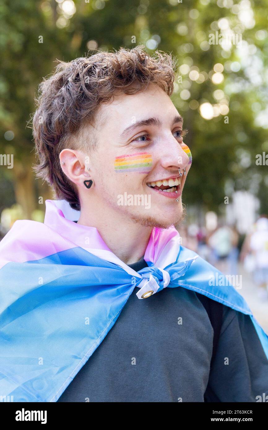 Young man with a joyful expression, draped in a pastel flag, with ...