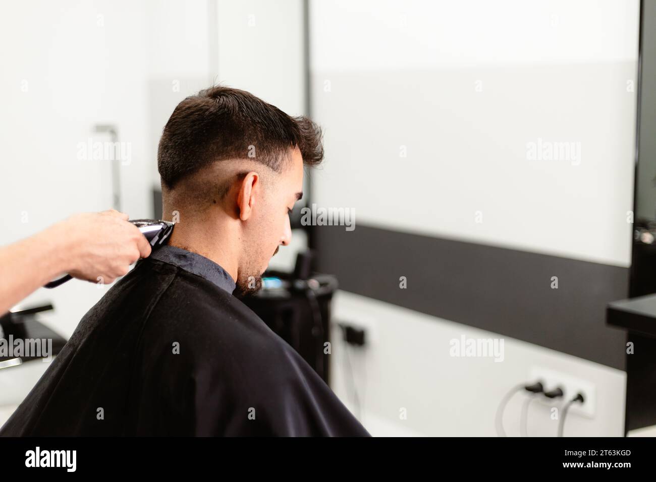 A young man receives a precise cut on the back of his head in a modern ...