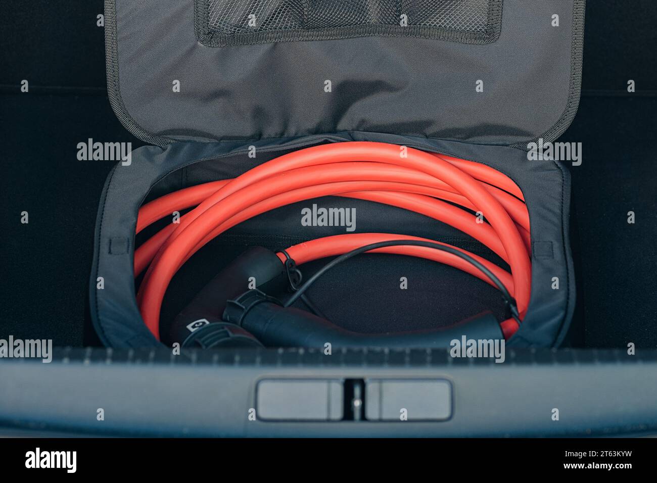 Orange electric vehicle charging cable neatly coiled inside a gray ...