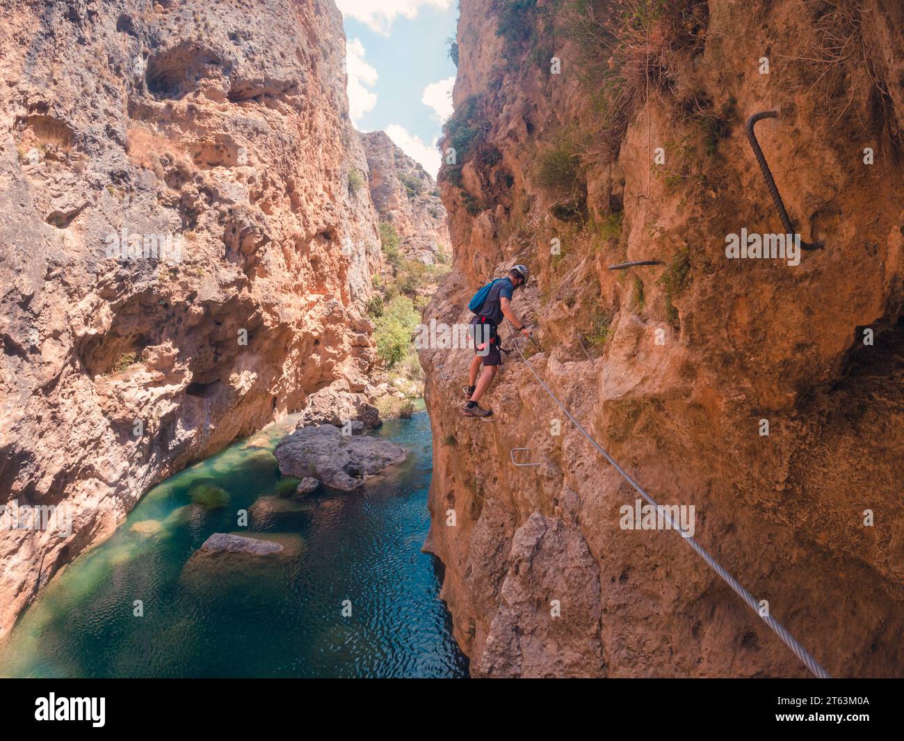 Side view of adventurous hiker traversing a cliff side path above a ...