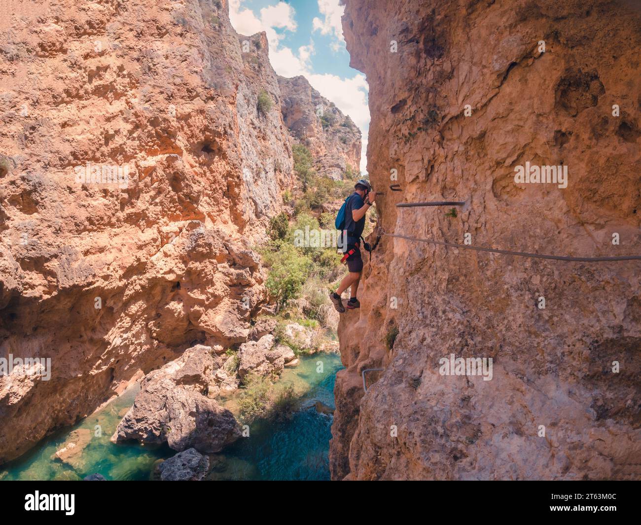 Side view of adventurous hiker traversing a cliff side path above a ...