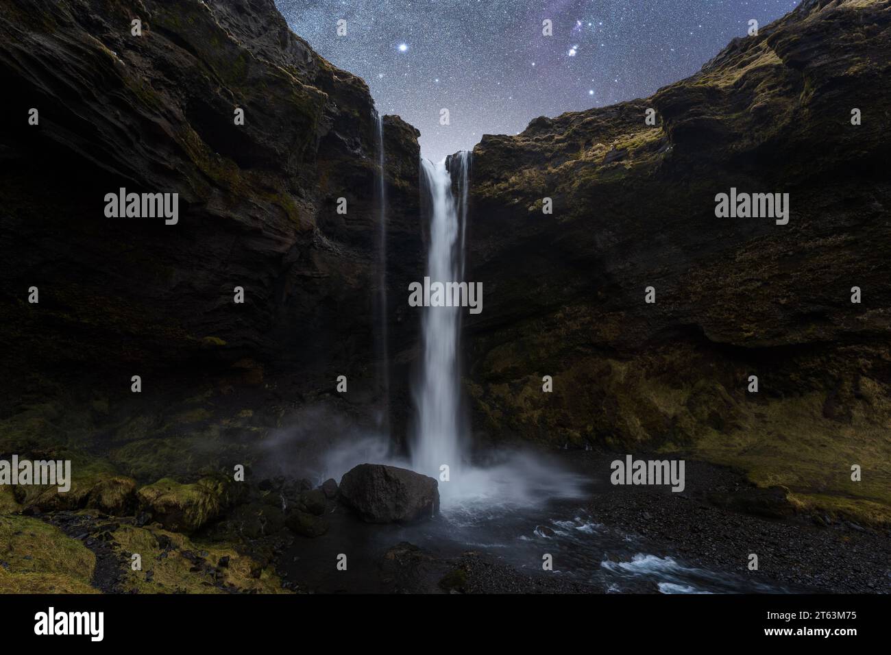 Majestic view of tall waterfall cascading from a rocky cliff with stars ...