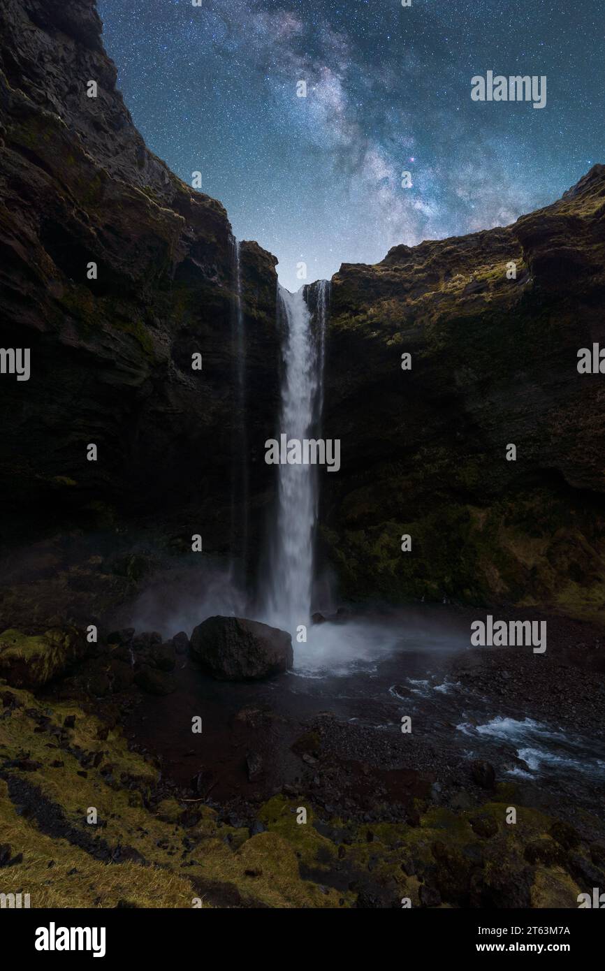 Majestic view of tall waterfall cascading from a rocky cliff with stars ...