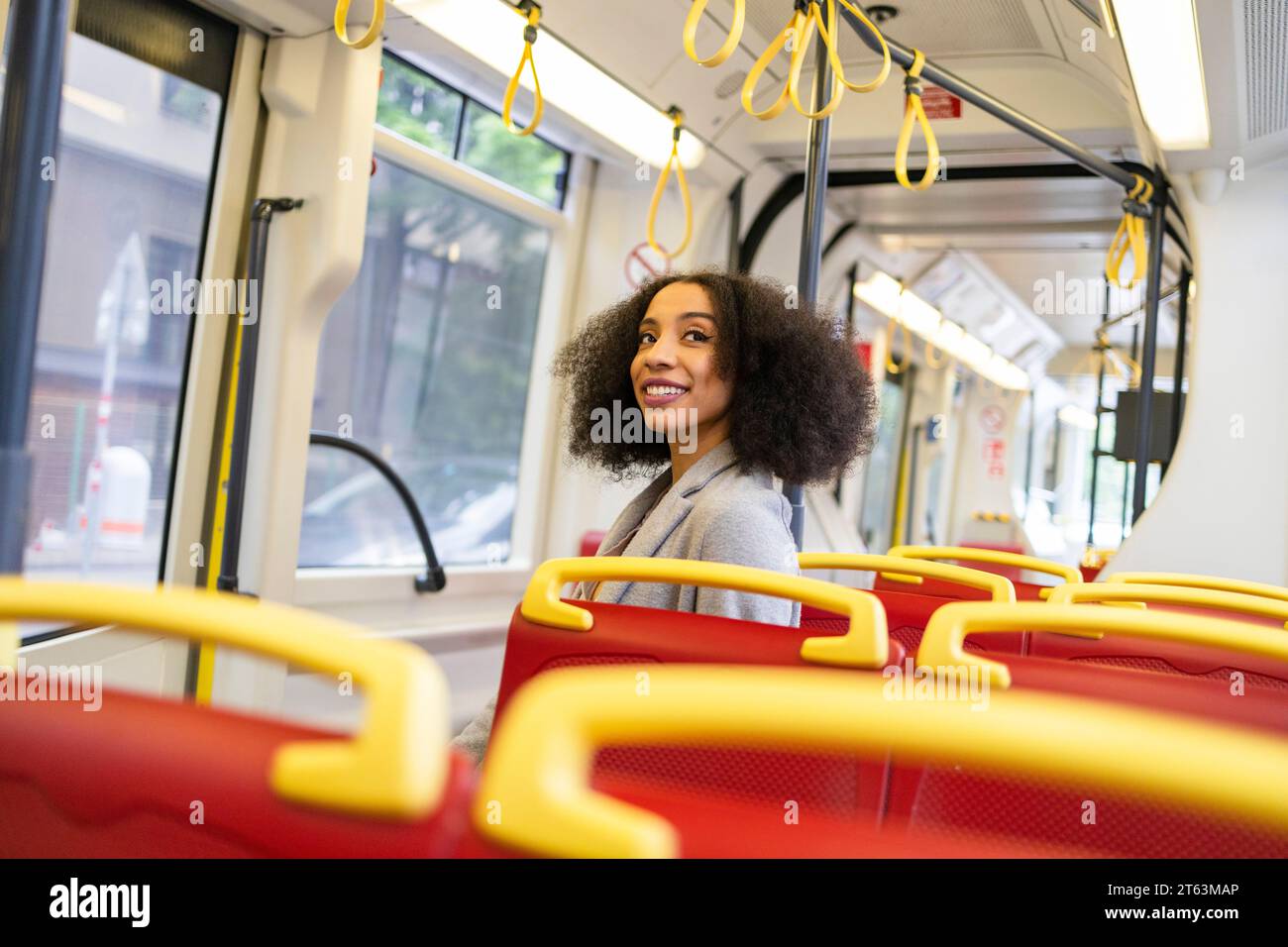 Happy ethnic woman with curly hair standing on city bus while looking ...
