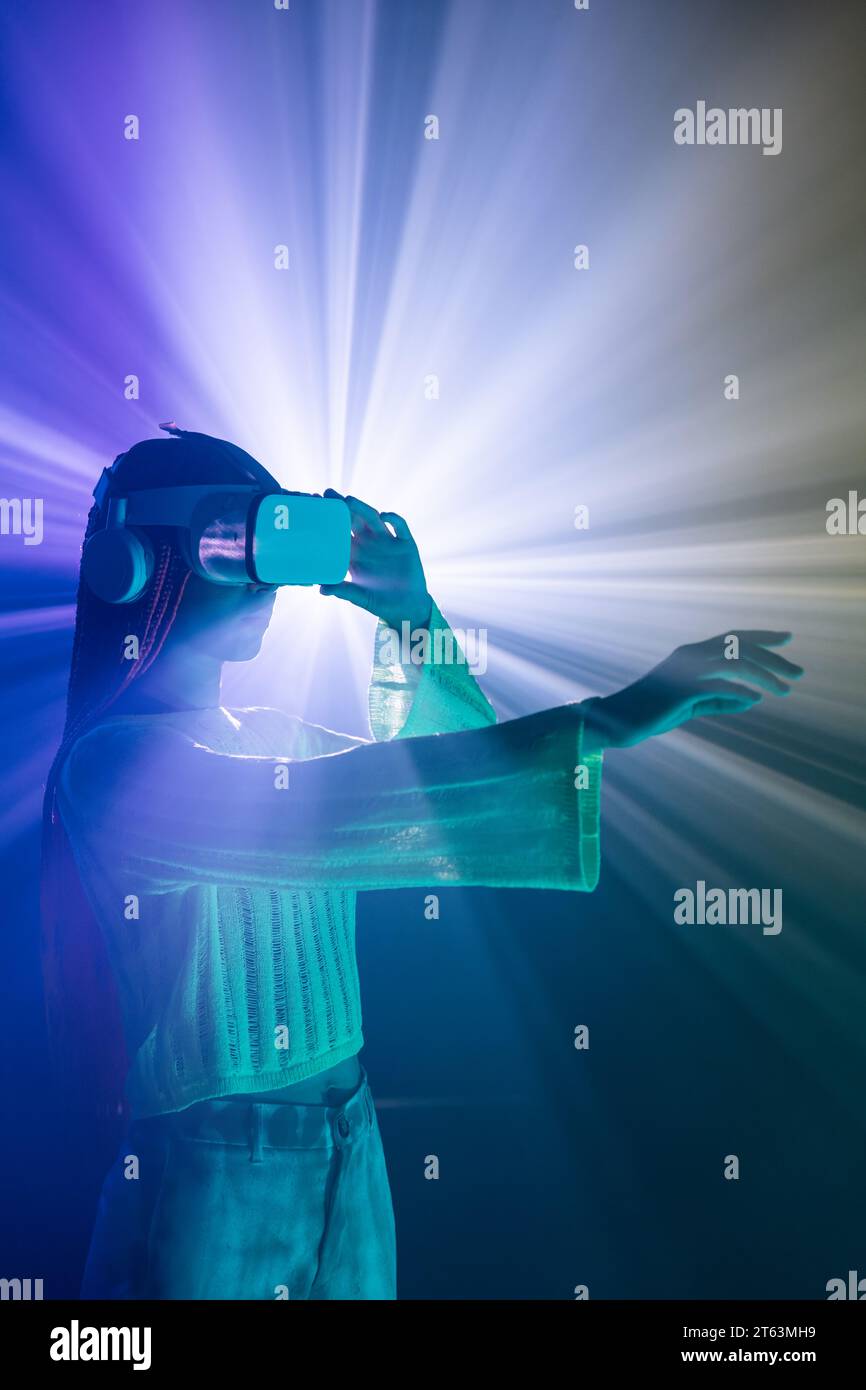 Side view of woman with orange braids wearing VR goggles and ...