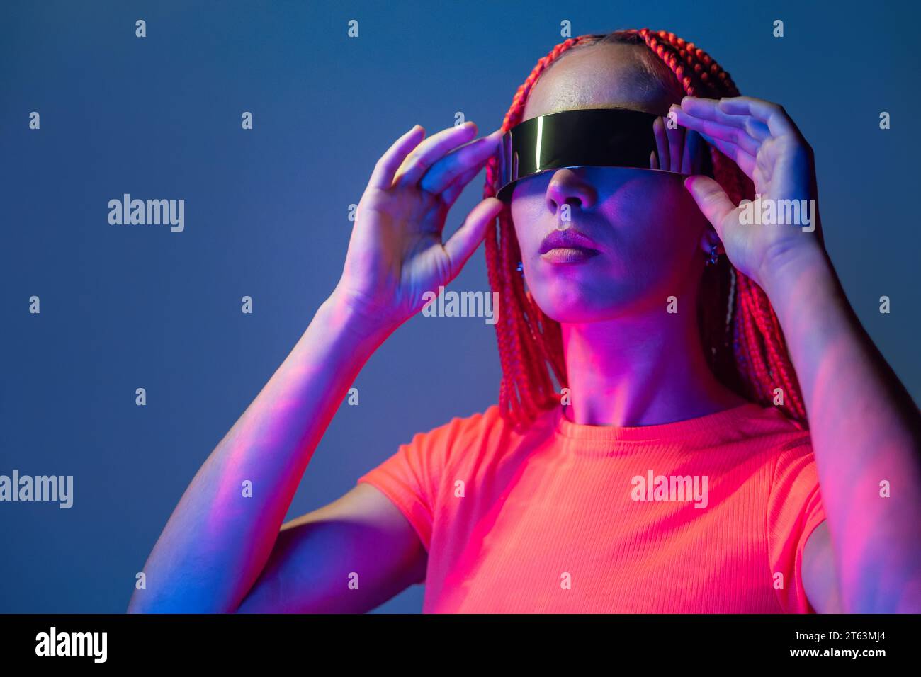 Beautiful woman with orange braids in trendy VR glasses experiencing ...