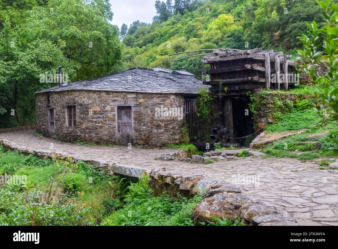 A picturesque stone built blacksmith workshop nestled in a lush green ...