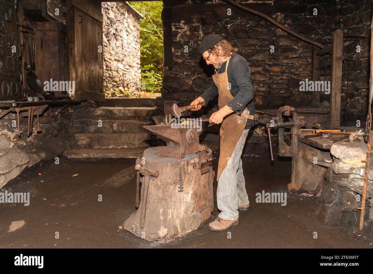 Side view of skilled blacksmith adorned in worn clothing meticulously ...