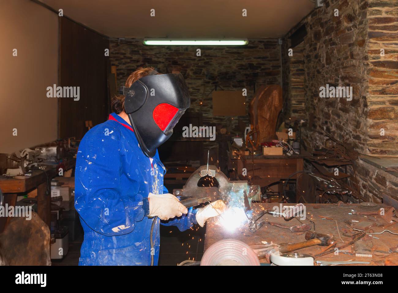 Skilled anonymous artisan sculptor uses welding equipment creating ...