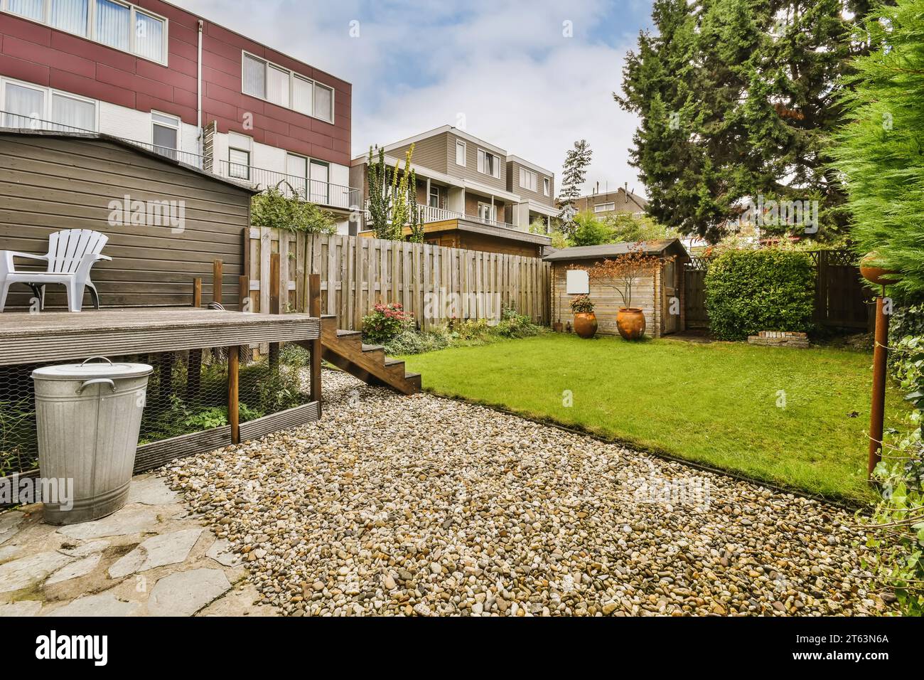 Backyard area with pebbles on field by grassy lawn and wooden shed ...