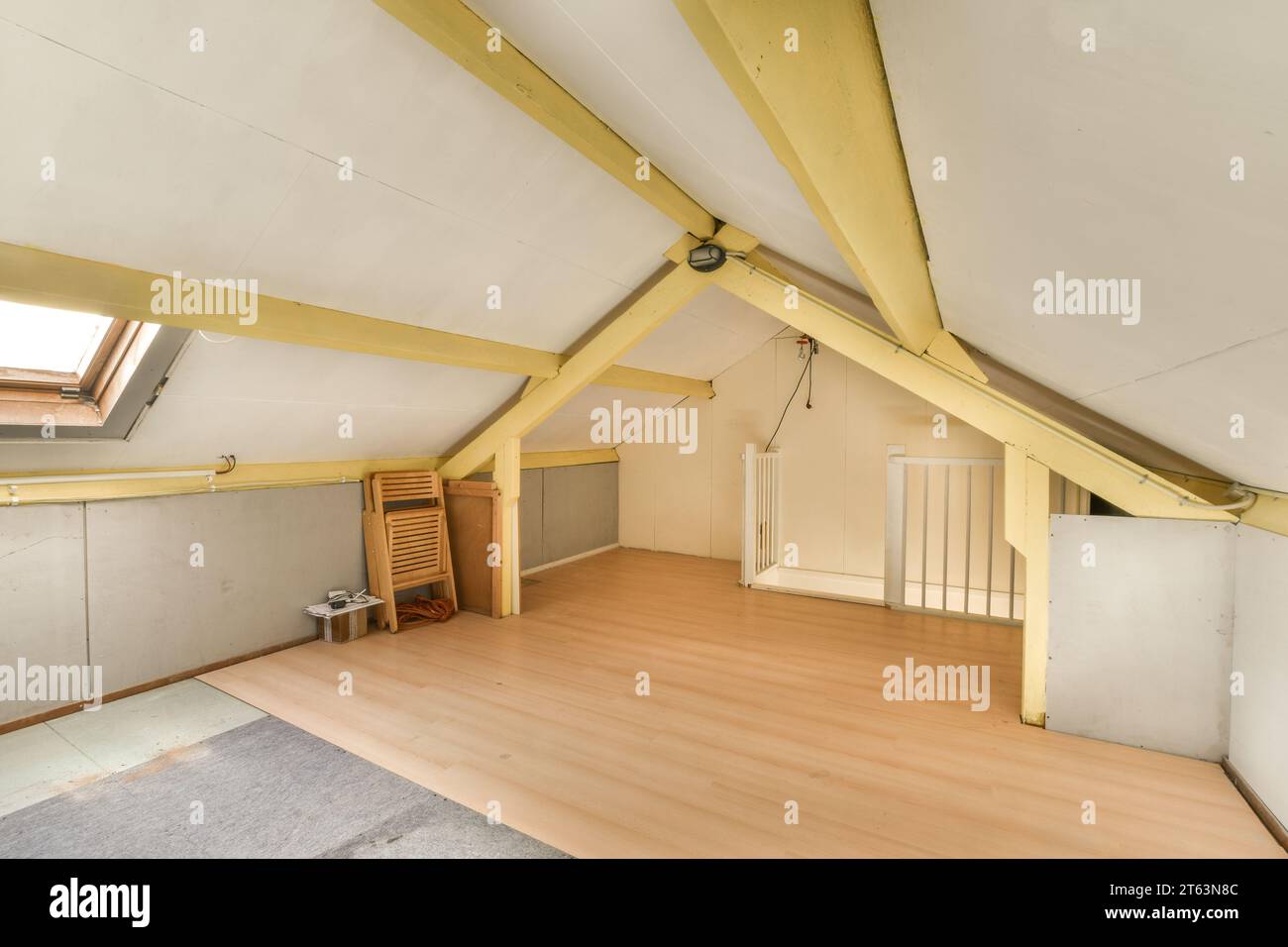 Interior of unfinished attic room with yellow beams and white ceiling ...