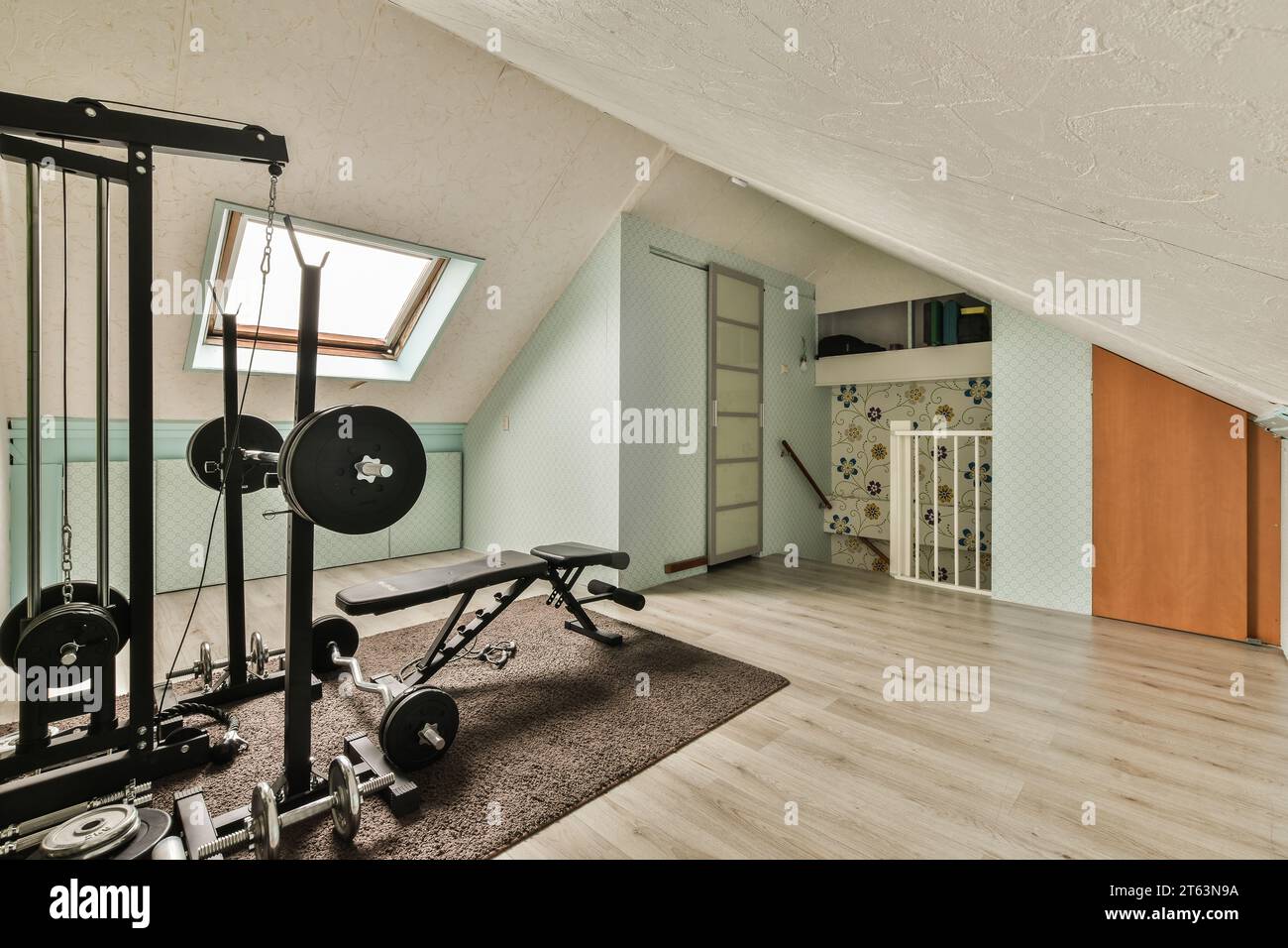 Weights with exercise bench by window in spacious attic room with light ...