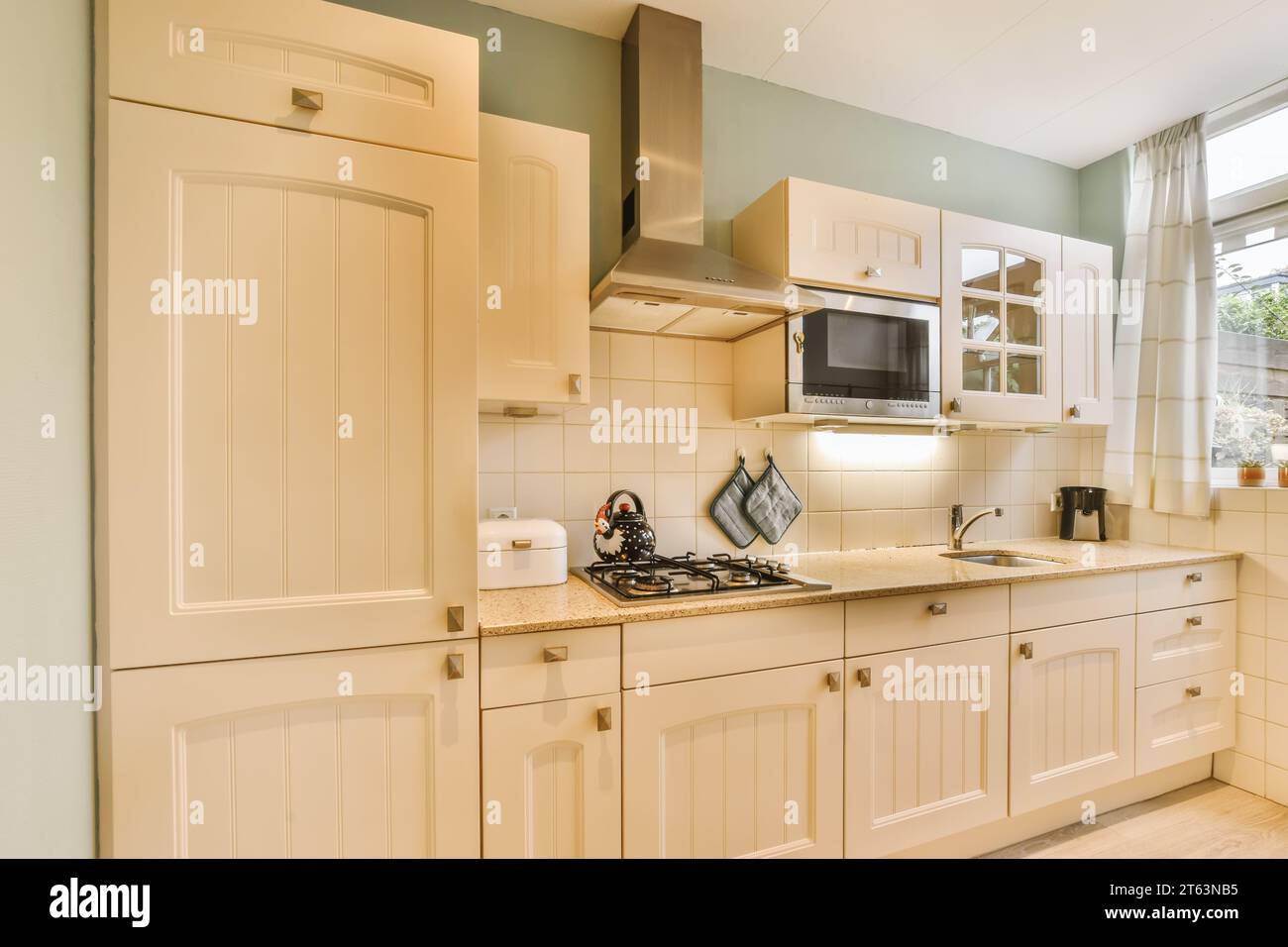 Rangehood over stove with sink at countertop in modern kitchen with ...