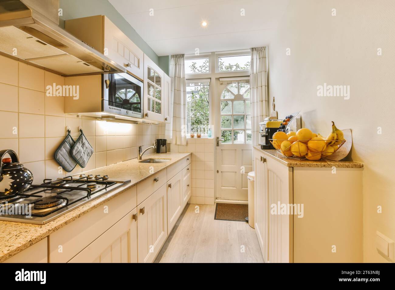 Interior of modern kitchen with appliances and beige cabinets against ...