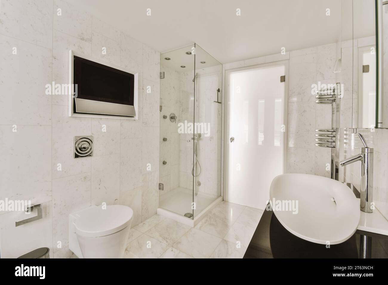 Interior of spacious tiled bathroom with glass shower booth and toilet ...