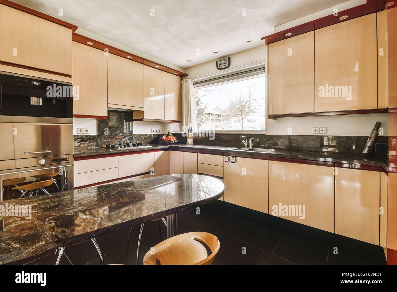 Dining table with chairs in front of spacious modern kitchen with ...