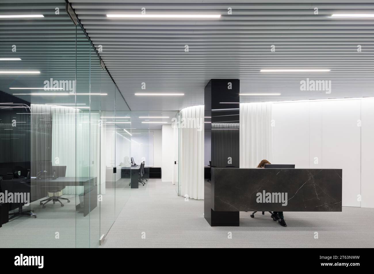Modern office space featuring sleek glass partitions, overhead linear ...