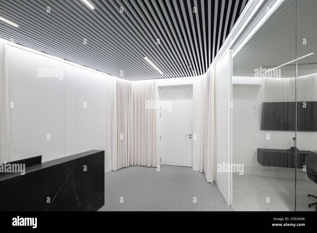 A modern interior space featuring a reception desk made of black marble ...
