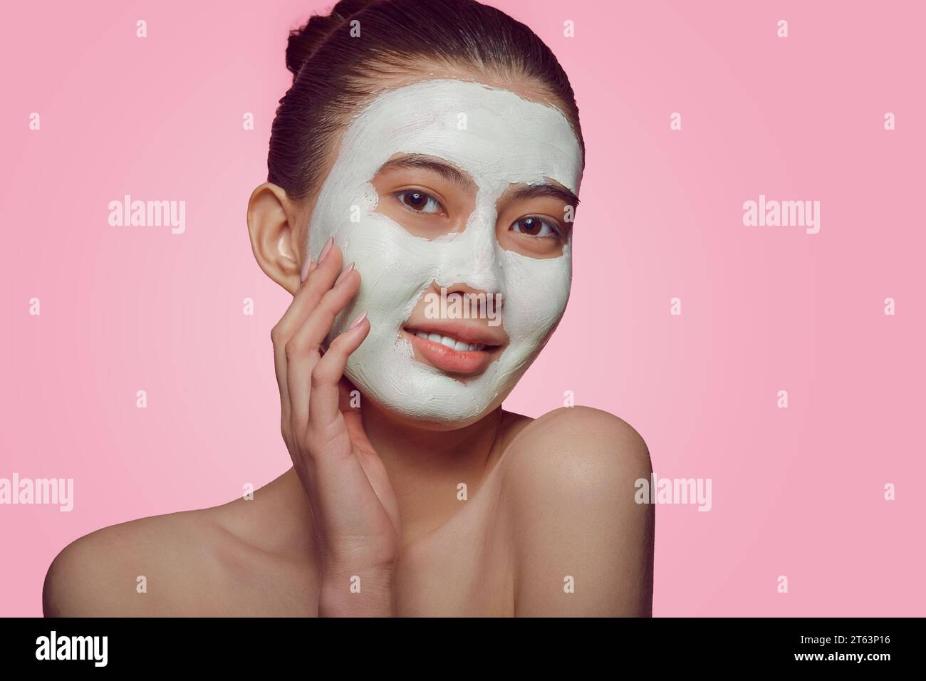 Close up portrait of a young female asian model applying clay face mask ...