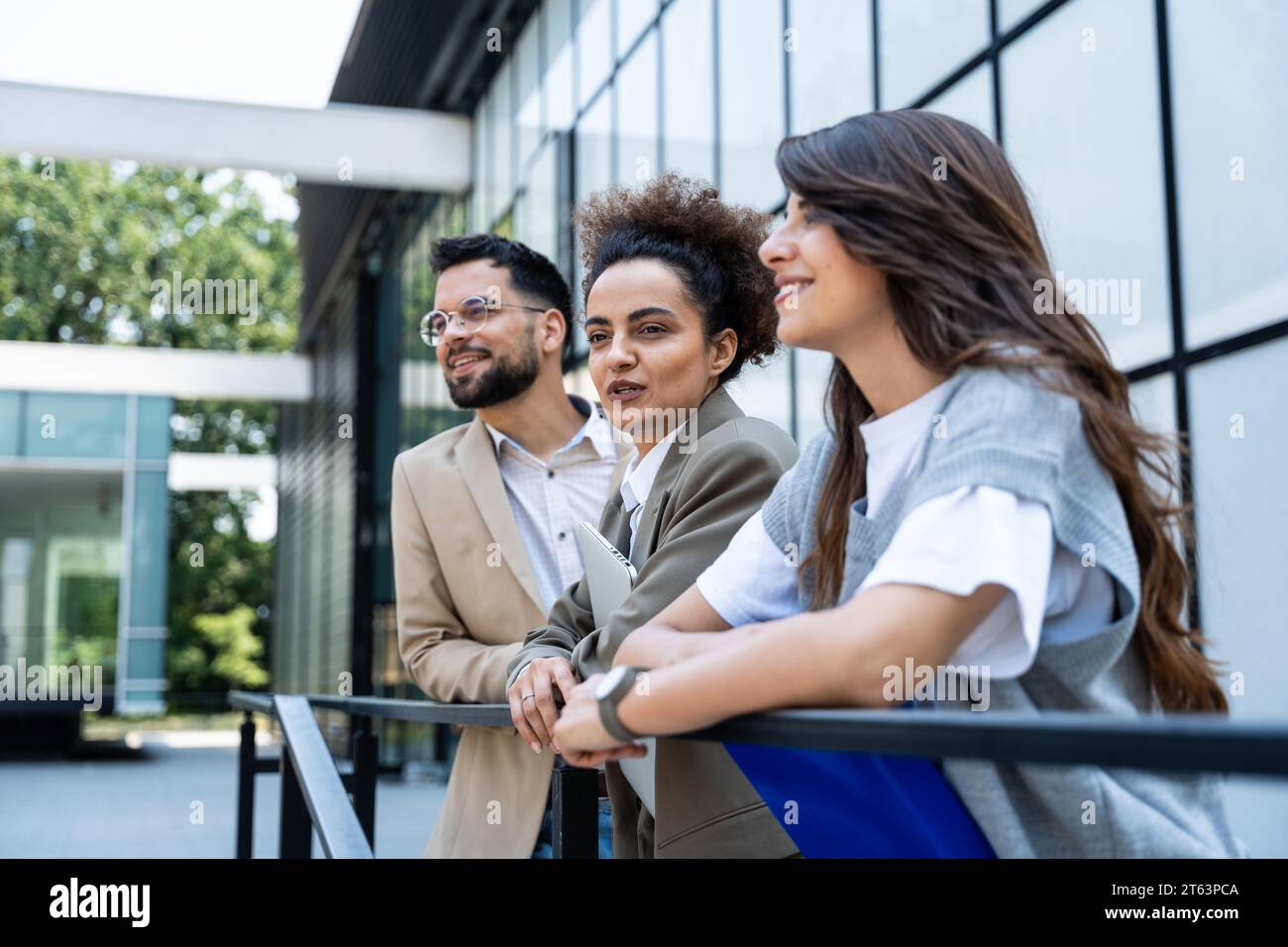 Three business people waiting in front of office building taking a ...
